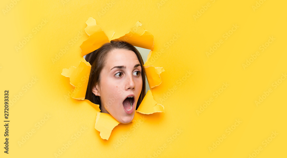 Surprised young woman through a hole paper looking lateral Stock Photo ...
