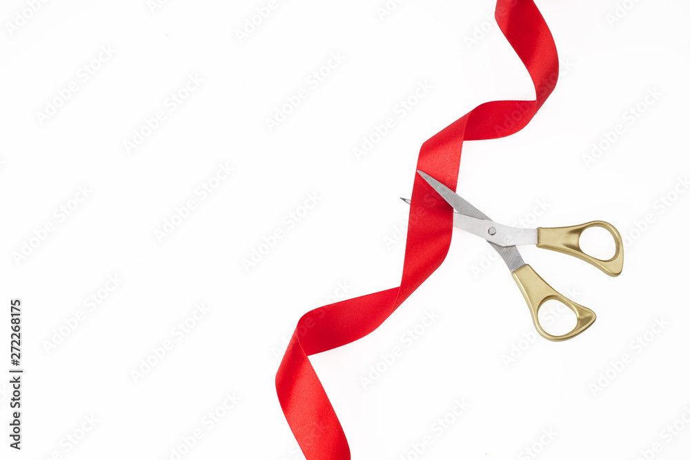 Grand opening. Top view of gold scissors cutting red ribbon on wite ...