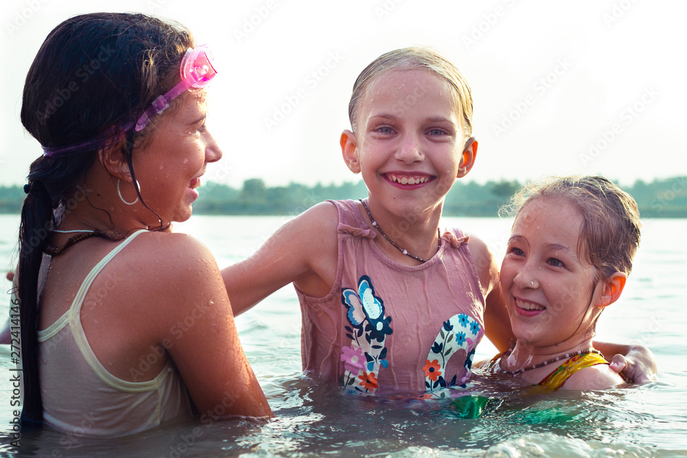 happy kids playing in the river in wet clothes. young friends swim in ...