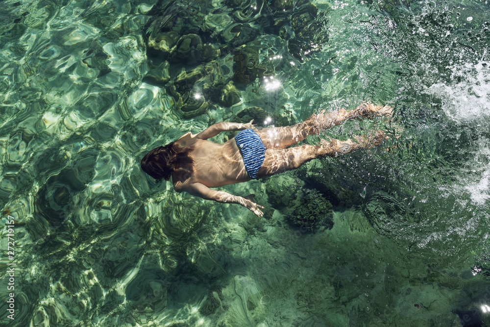 Shirtless girl swimming in sea Stock Photo | Adobe Stock