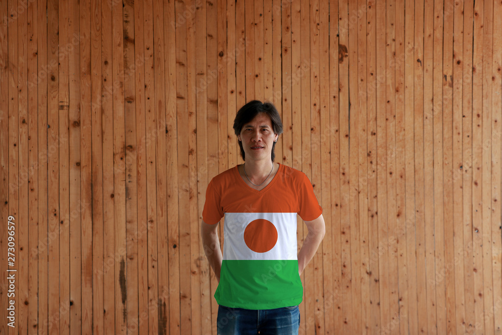 Man wearing Niger flag color of shirt and standing with crossed behind ...