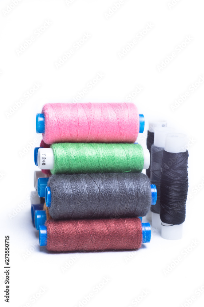 Spools of thread laid horizontally on top of each other on white ...
