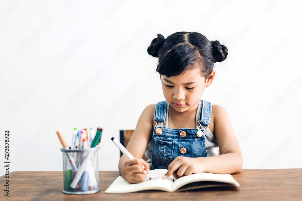 School kid little girl learning and writing in notebook with pencil ...