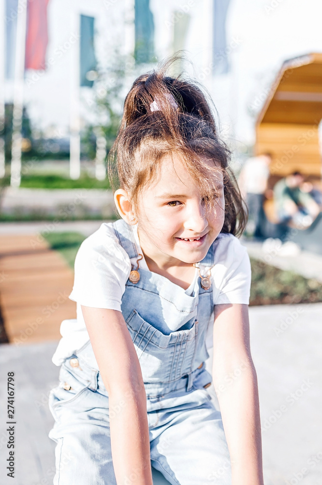 Cute happy caucasian girl in denim overalls on a swing. Lifestyle Stock ...