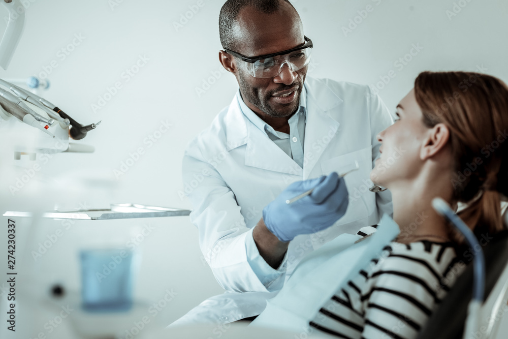 Concentrated dark-skinned doctor curing his female patient teeth Stock ...