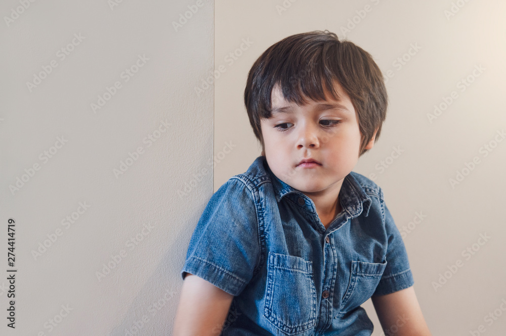 Emotional portrait of Unhappy boy sitting next to wall with sad face ...