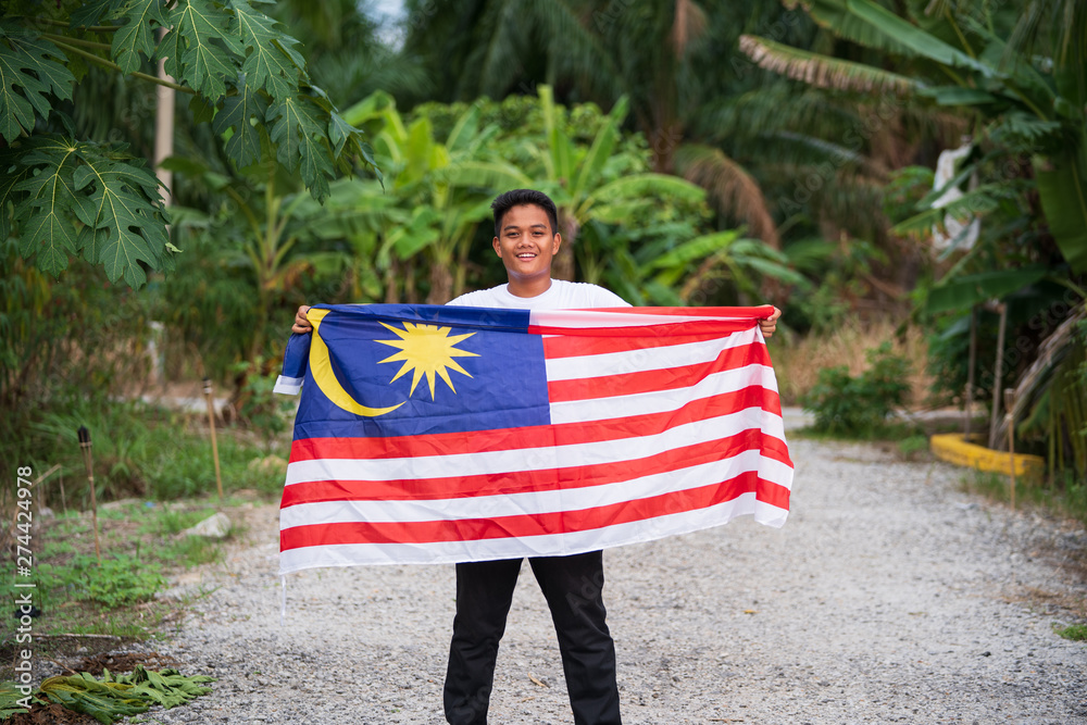 Portrait of young Malay Asian man standing, holding and waving ...