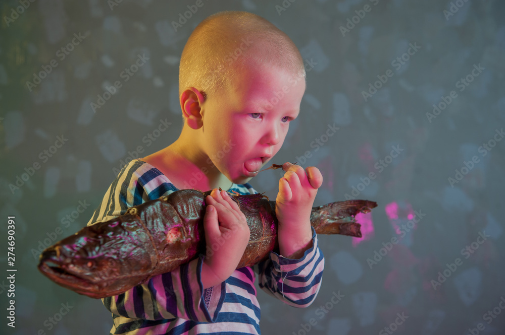 Little blond boy shows big smoked fish. Child wants to catch big fish ...