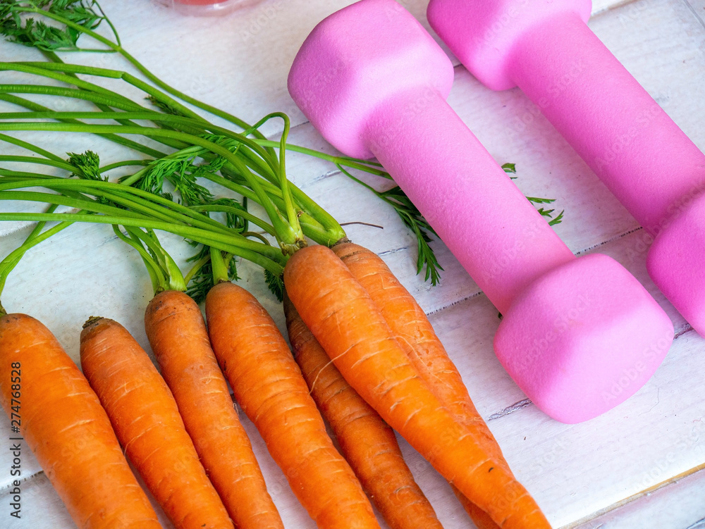 Bunch of fresh carrot with dumbbells . Concept carrot for health ...