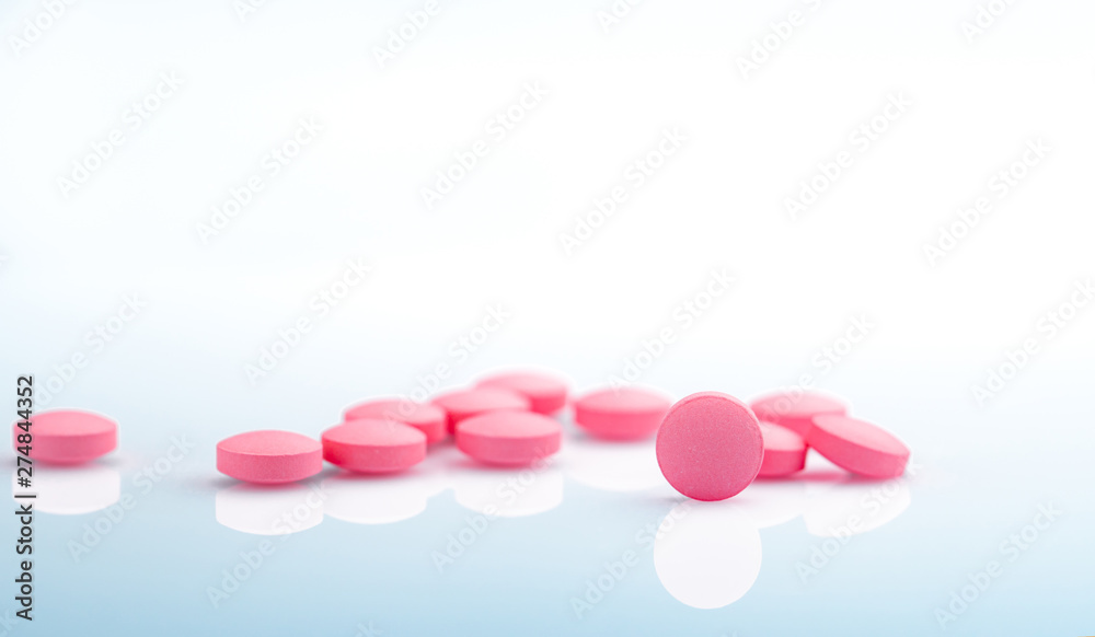 Round pink tablets pill on white background. Vitamins and minerals plus ...