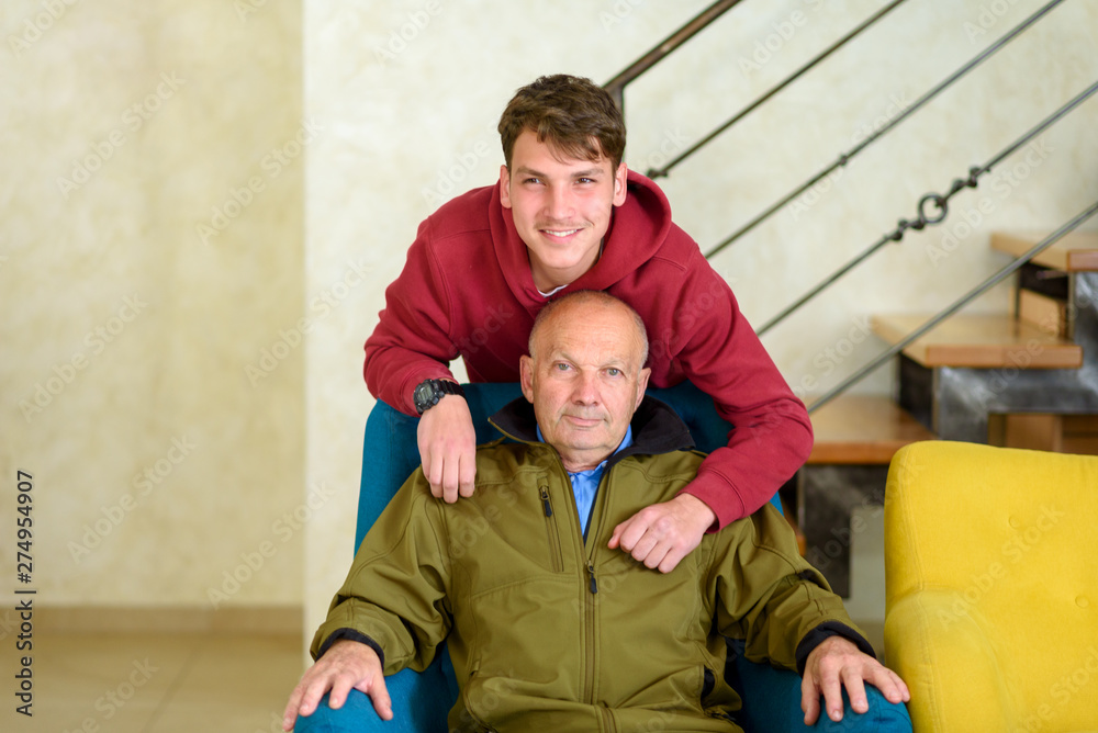 Senior father and young smiling son looking away in a home. Happy old ...