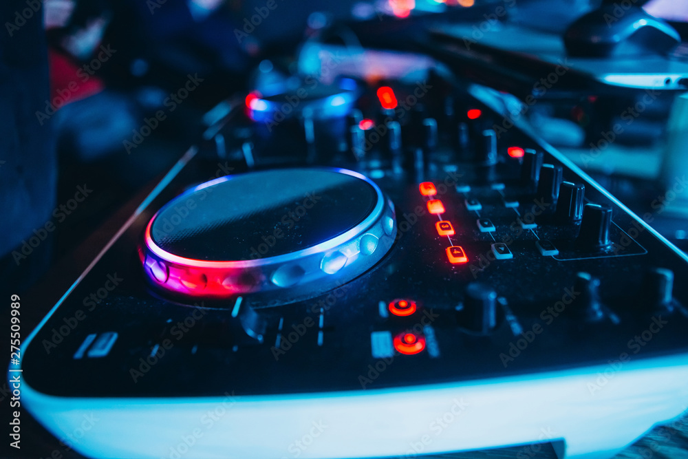 control DJ for mixing music with blurred people dancing at party in ...