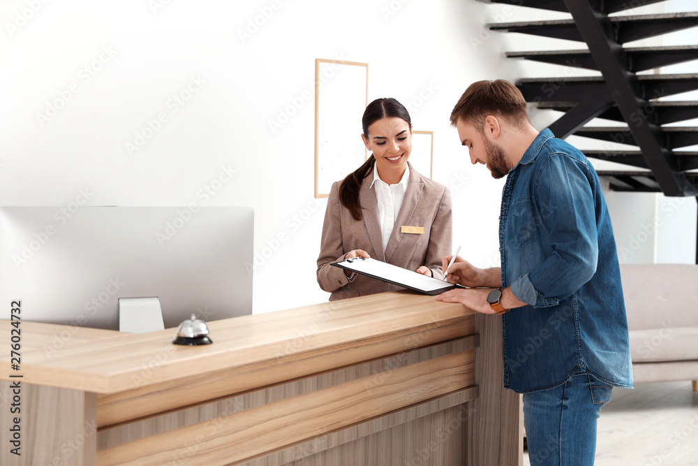 Professional receptionist working with client at desk in modern hotel ...