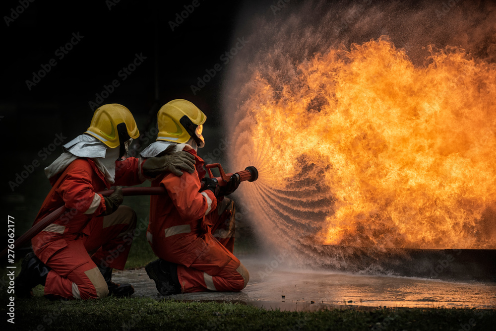 2 firefighters spraying water in fire fighting operation, Fire and ...
