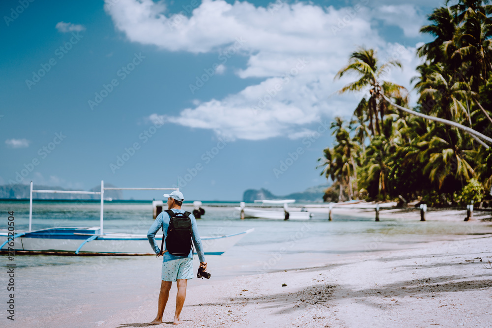 Back view of the man photographer with camera on pristine beach ...