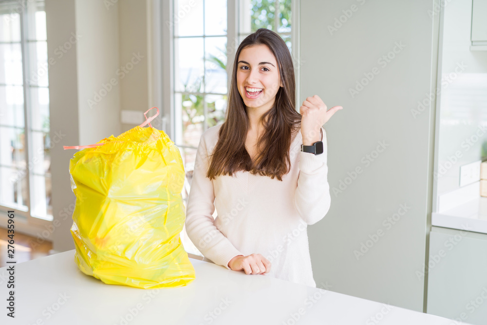 Beautiful young woman taking out the garbage from the rubbish container ...