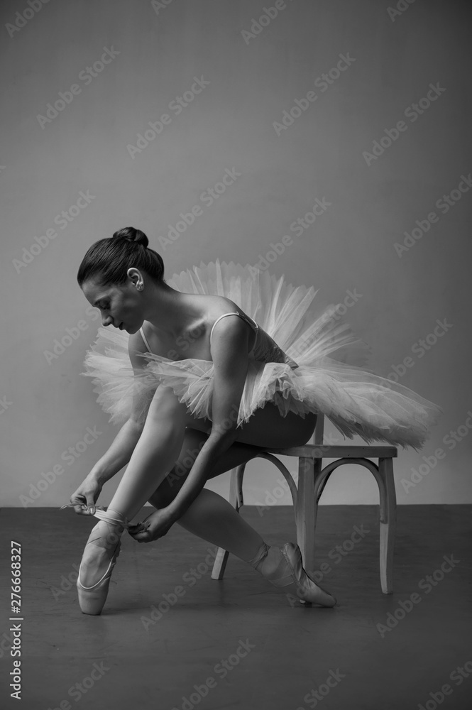 ballet dancer on a chair and tying her ballet slippers, black white ...
