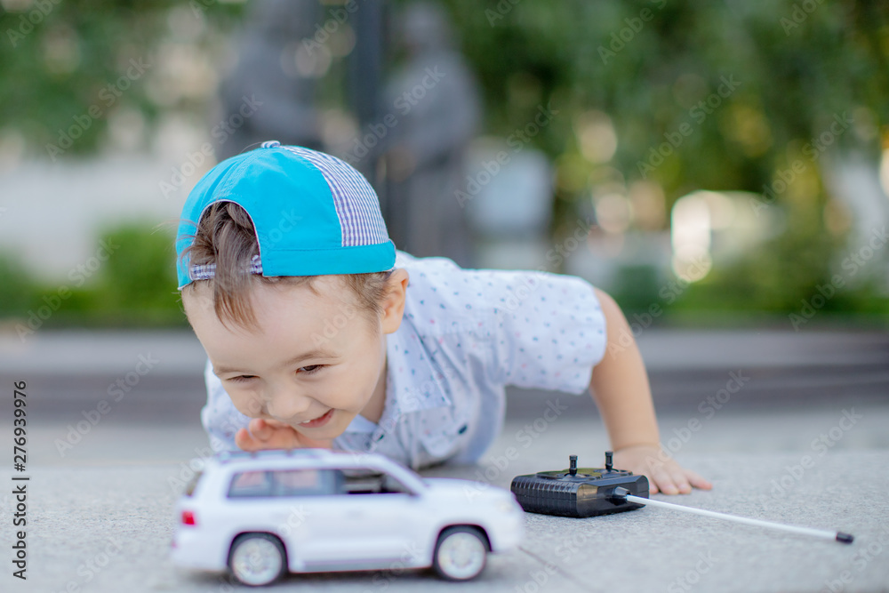 The boy is controling the toy car with a remote control. child's face ...
