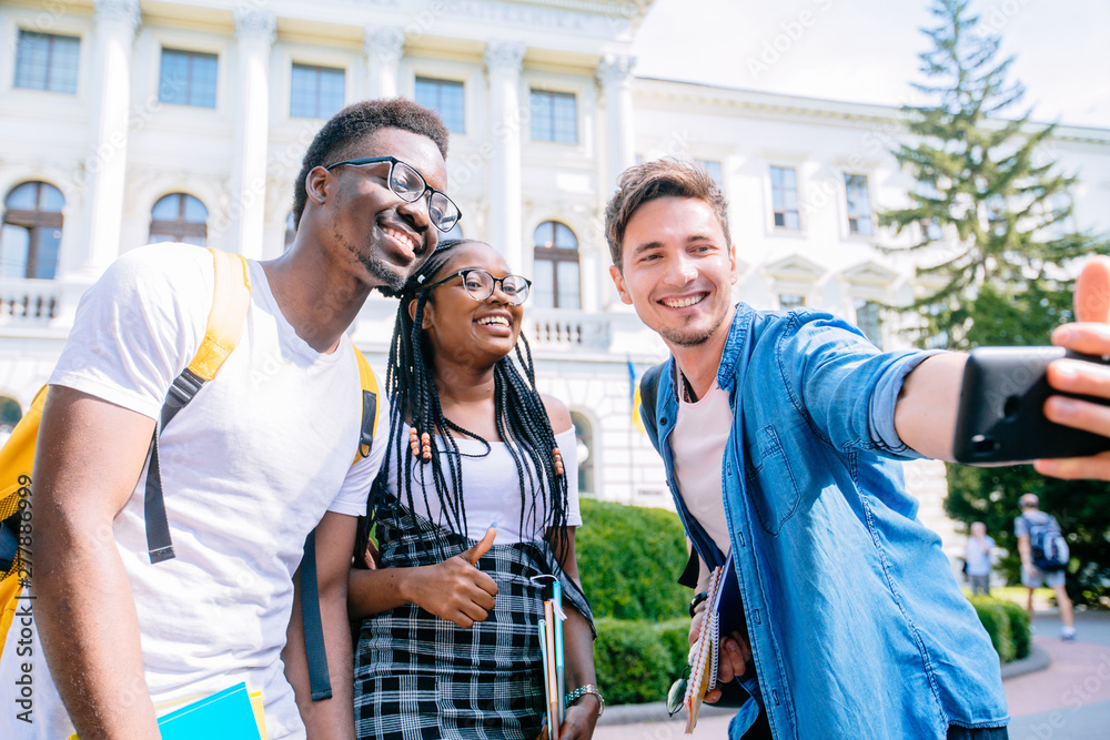 Three multiracial friends students having fun and joking together ...