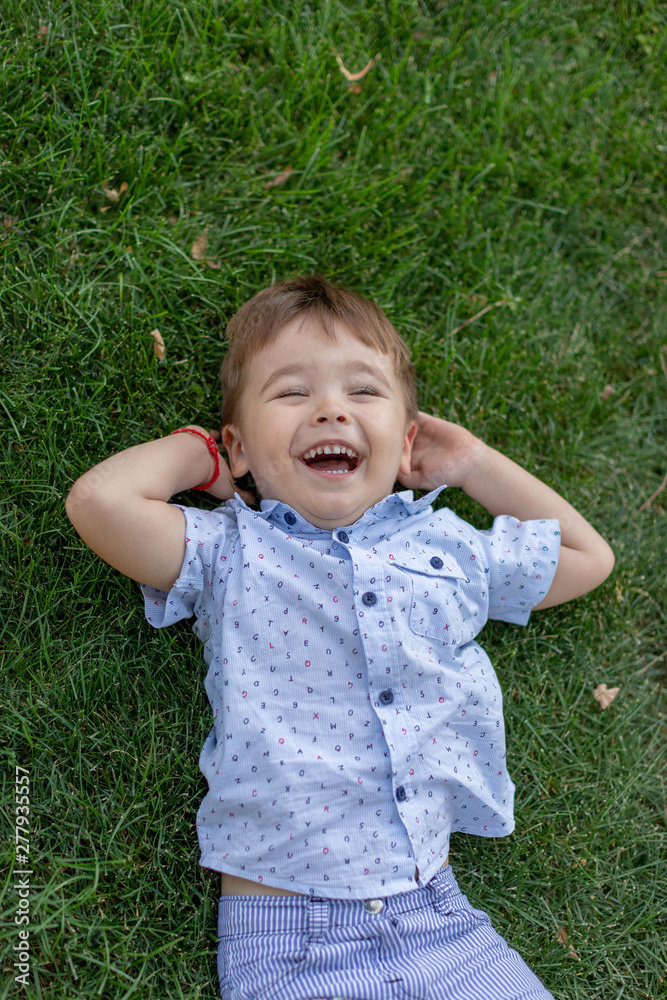 Emotional portrait of a happy and cheerful little boy laughing lying on ...