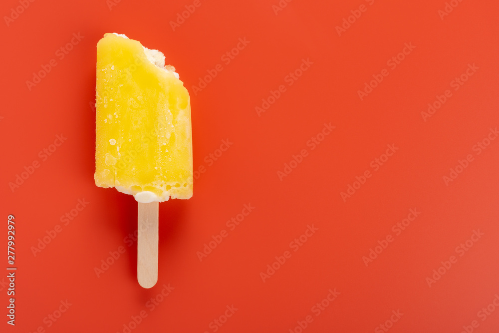 yellow popsicle with a couple of bites on an orange background Stock ...