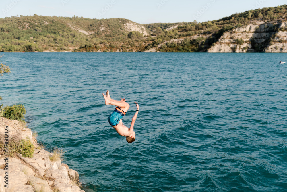teen boy doing a back flip off a cliff in a lake in Provence Stock ...