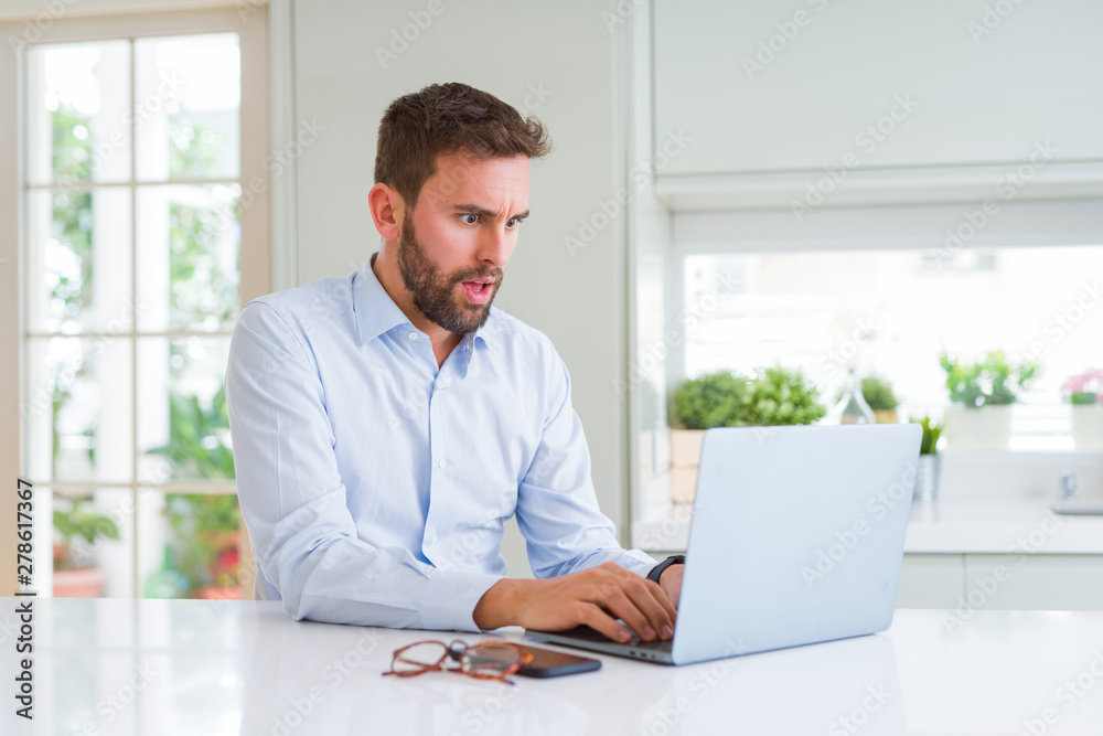 Handsome business man working using computer laptop scared in shock ...