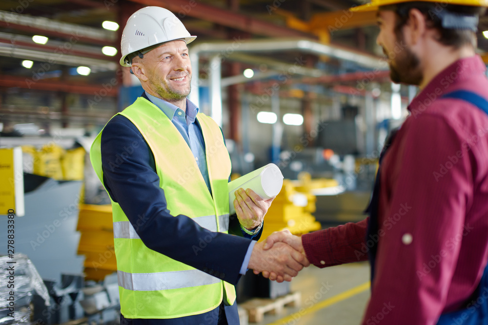 Engineer and foreman shake hands after successfully discussing a new ...