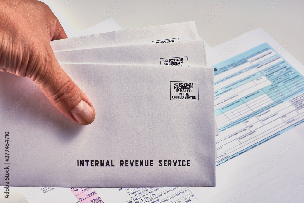 Human holds in hand three mails from the Internal Revenue Service next ...