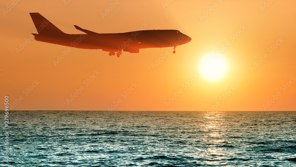 airplane flying over sea water on sunset sky background side panorama ...