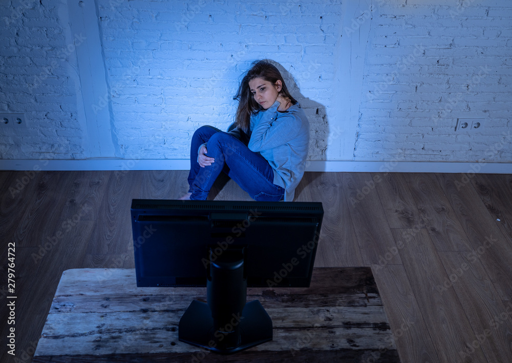 Scared and sad young woman on the floor staring a computer suffering ...