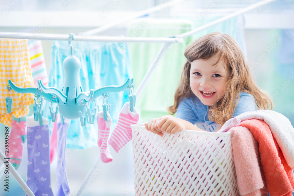 Child in laundry room. Clean washed clothes on drying rack. Mother's ...