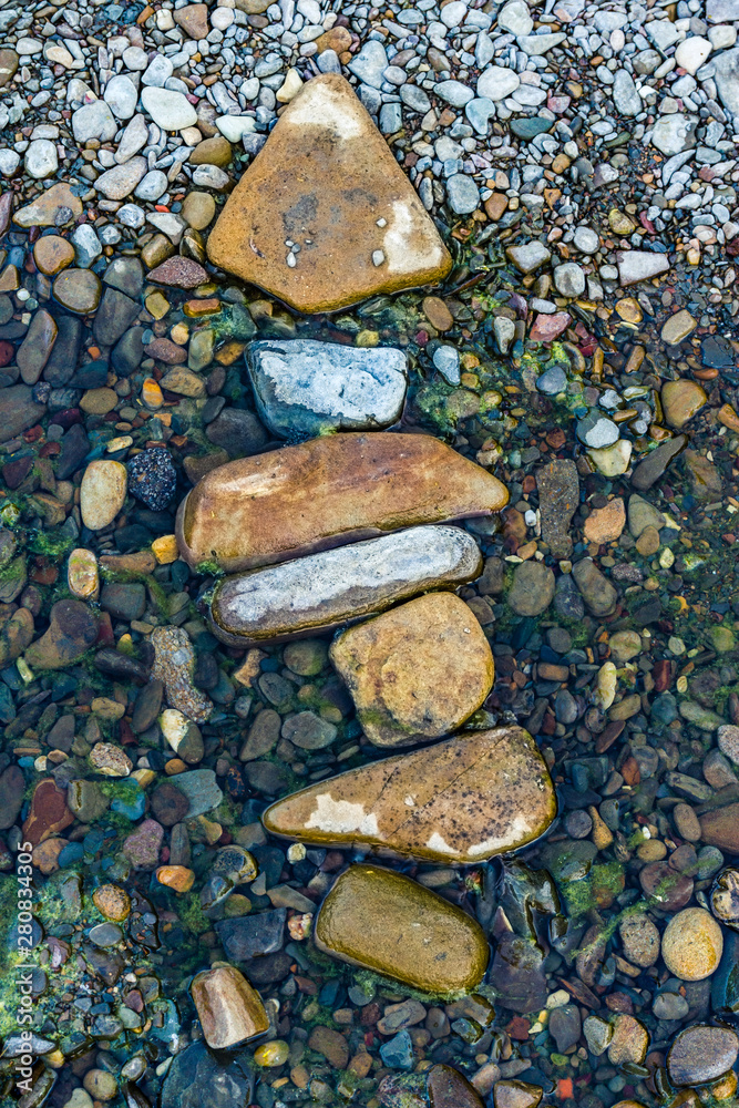 River stones laid out in the form of a pointer, a river bridge of ...