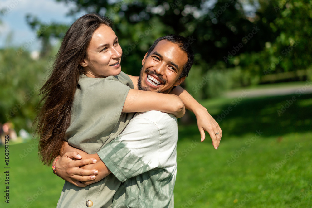 Happy mixed love couple hugging in park on background greenery. hot ...