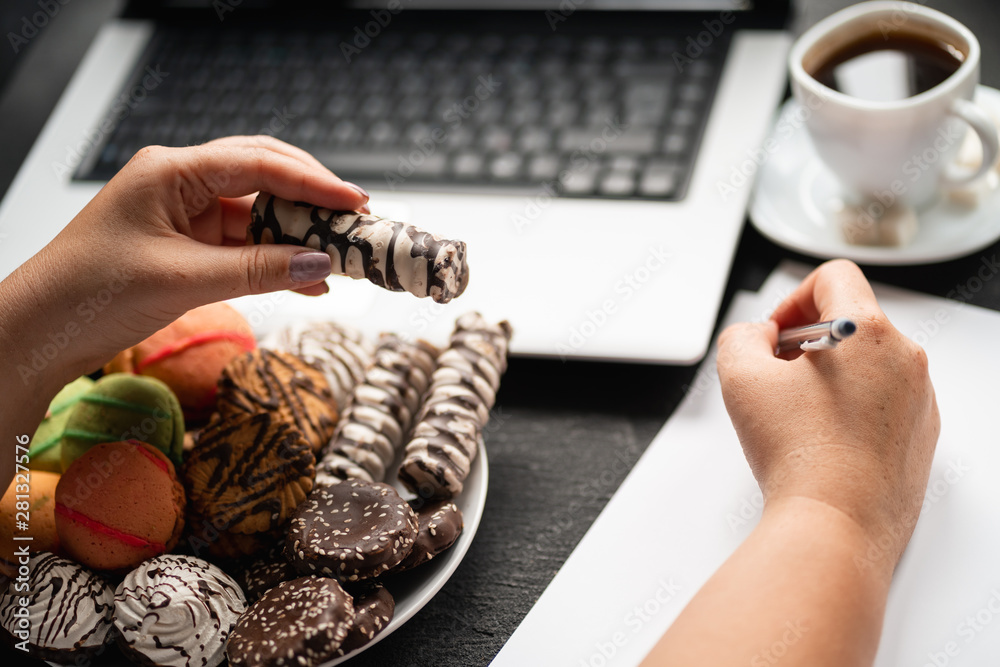 Unhealthy snack at work time. Woman eating chocolate cookies and ...