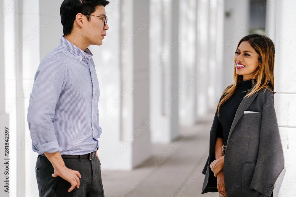 Two young and confident professional Asian business people stand and ...