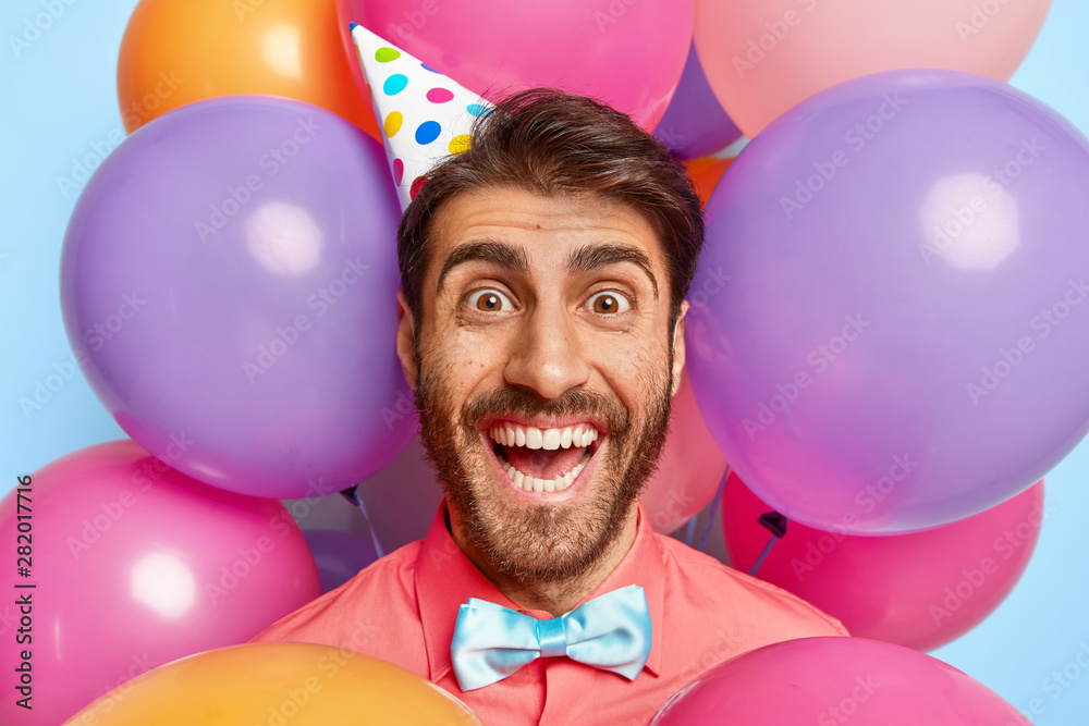 Lucky cheerful man with happy look, makes photo against party ...
