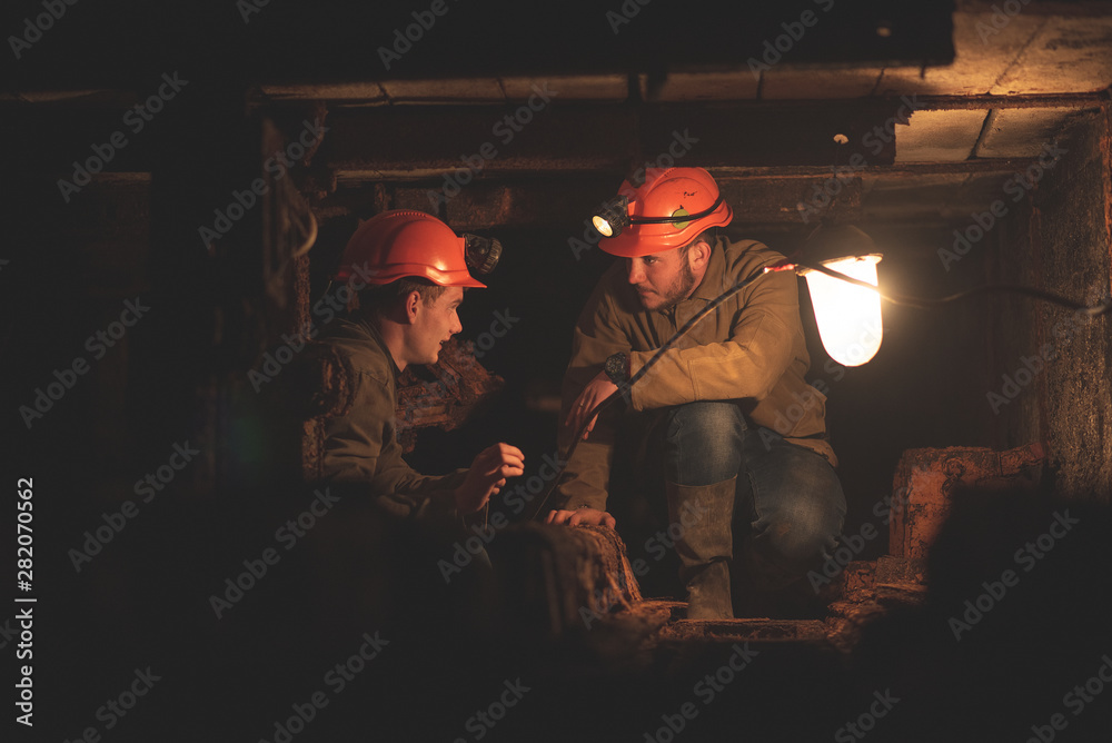 Two young guys in a working uniform and protective helmets, sitting in ...