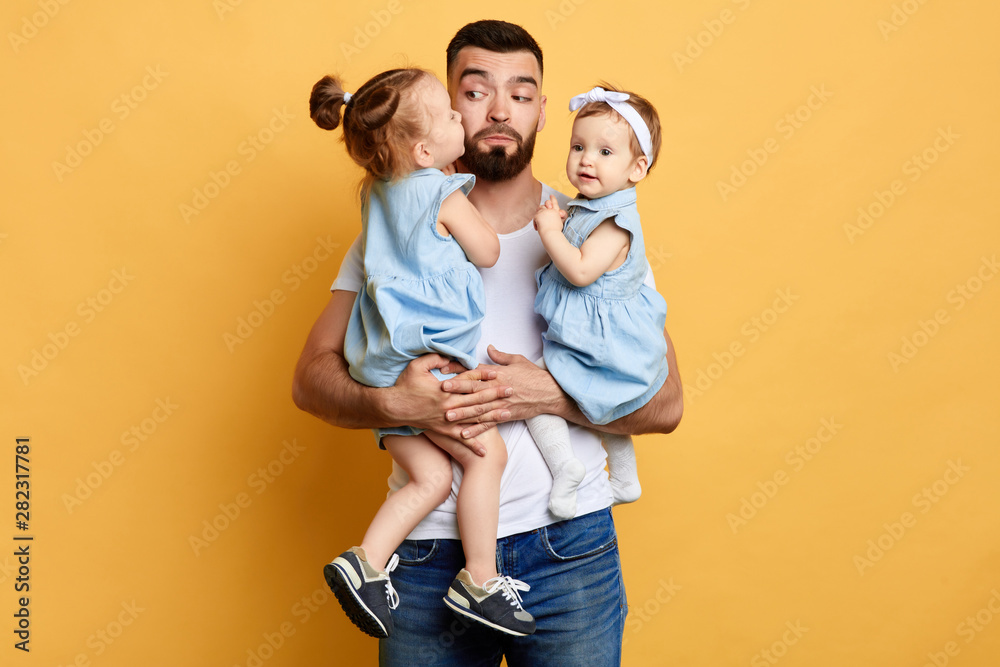two adorable little girls adore, love, kiss their daddy. isolated ...