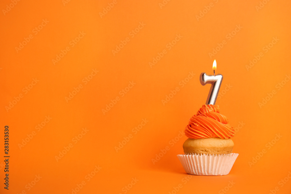 Birthday cupcake with number seven candle on orange background, space ...