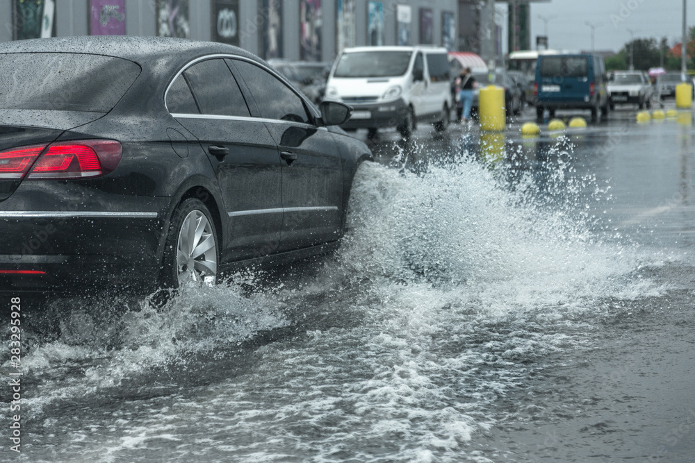 Driving car on flooded road during flood caused by torrential rains ...