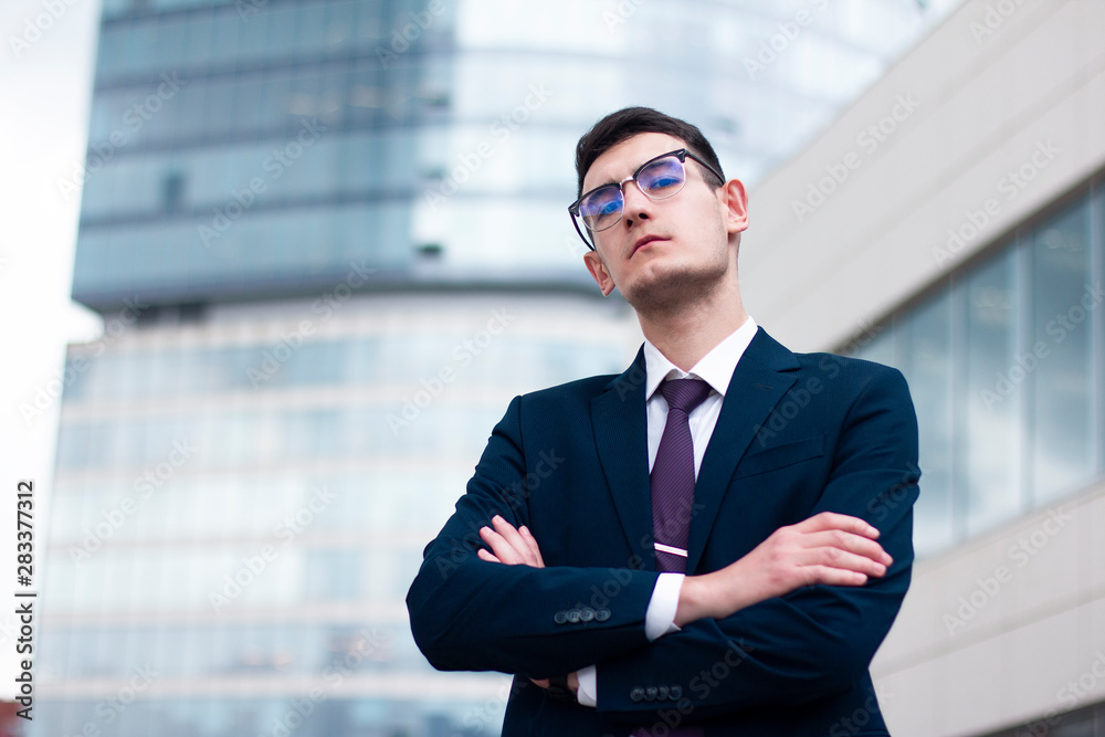 Serious arrogant young businessman in a suit with tie and in glasses ...