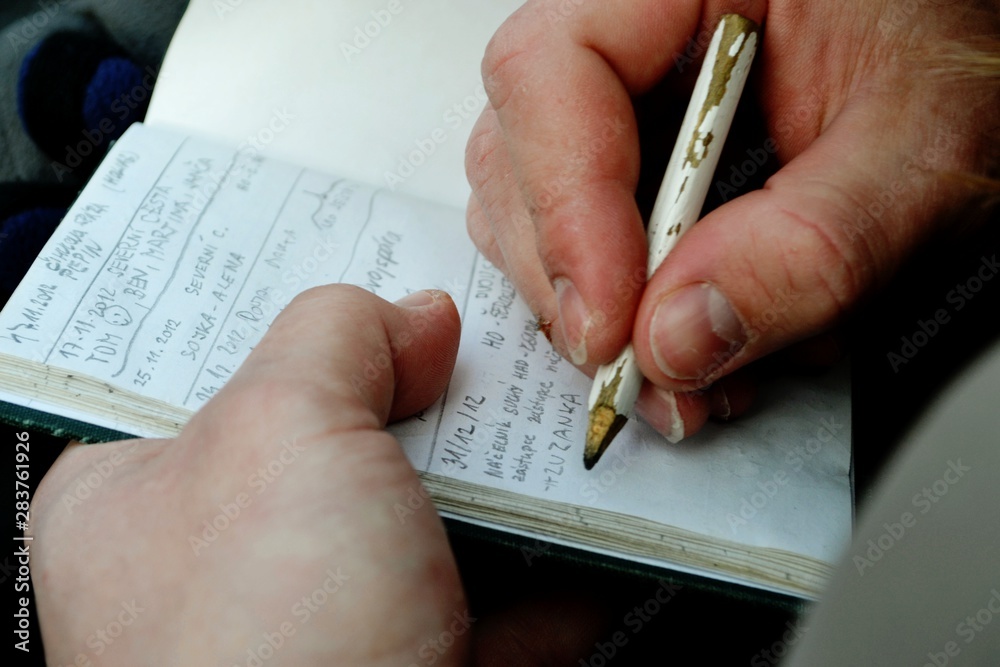 At the top of the rock, young man is writing down the route he just ...