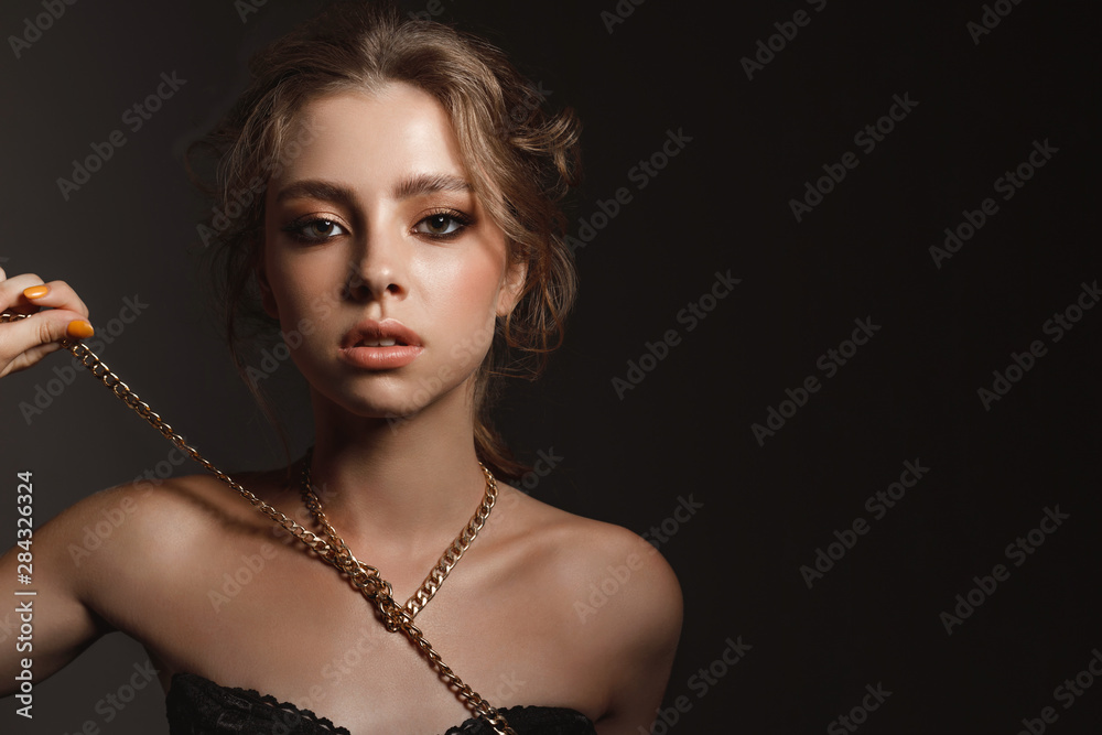 Portrait of a young girl with blond hair, she holds a golden chain ...