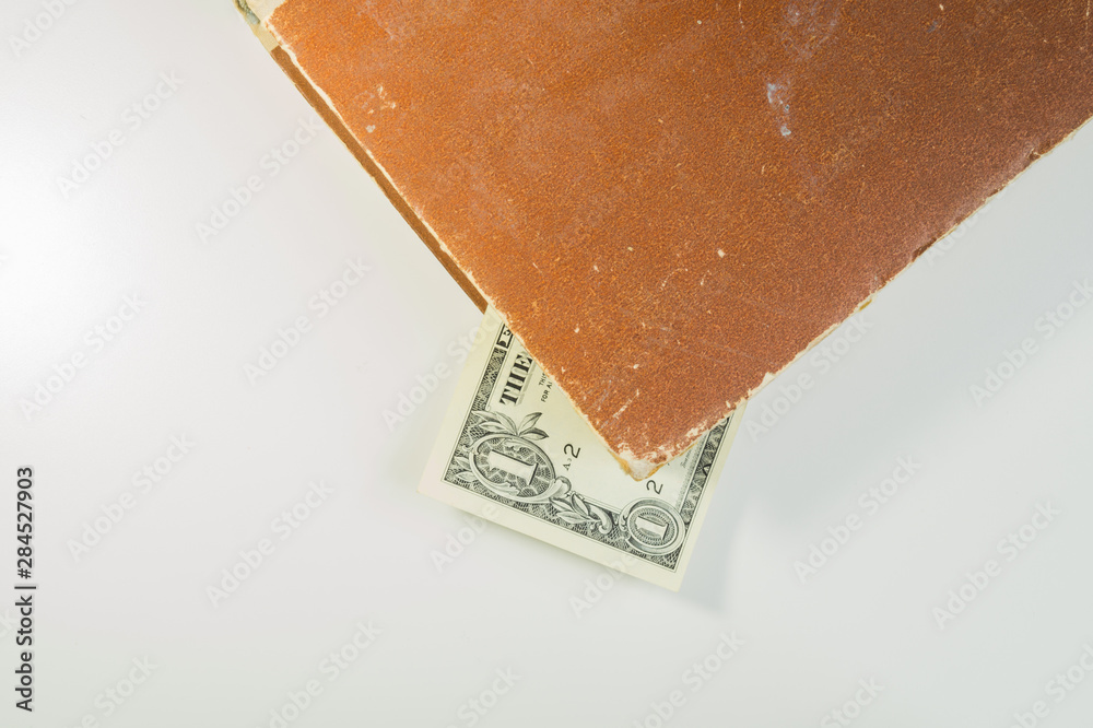 Money in a book. dollar bill used as a bookmark in the book on a white ...