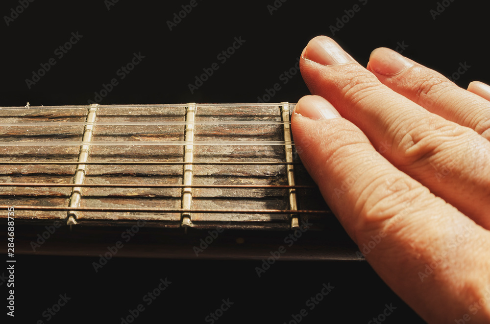 Foto Fingers muffling the sound of the strings of an old acoustic ...