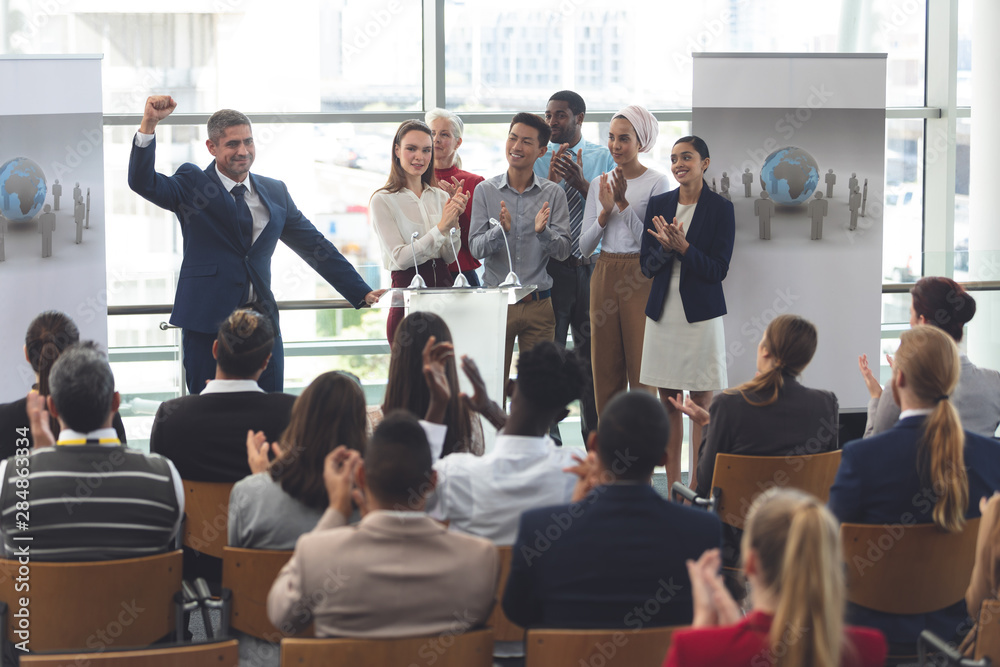 Businessman standing at podium with colleagues and speaks in a business ...