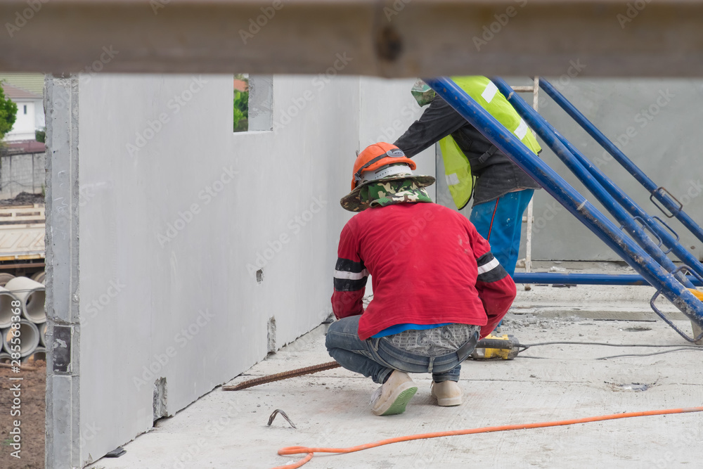 Construction worker are installing the precast concrete wall, orange ...