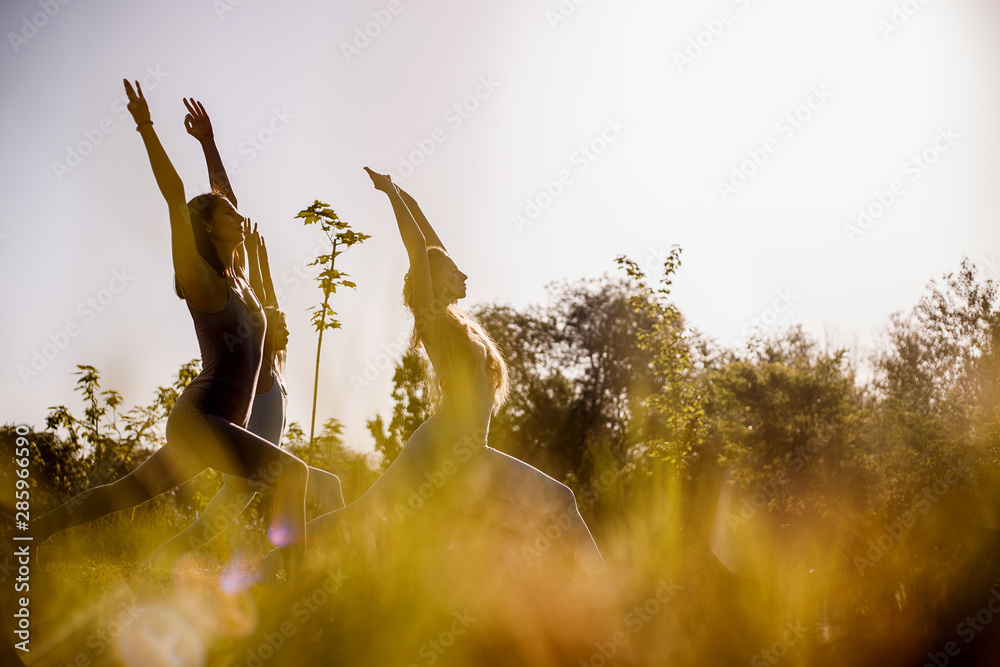 Foto Four young women are practising yoga in the open air in the nature ...