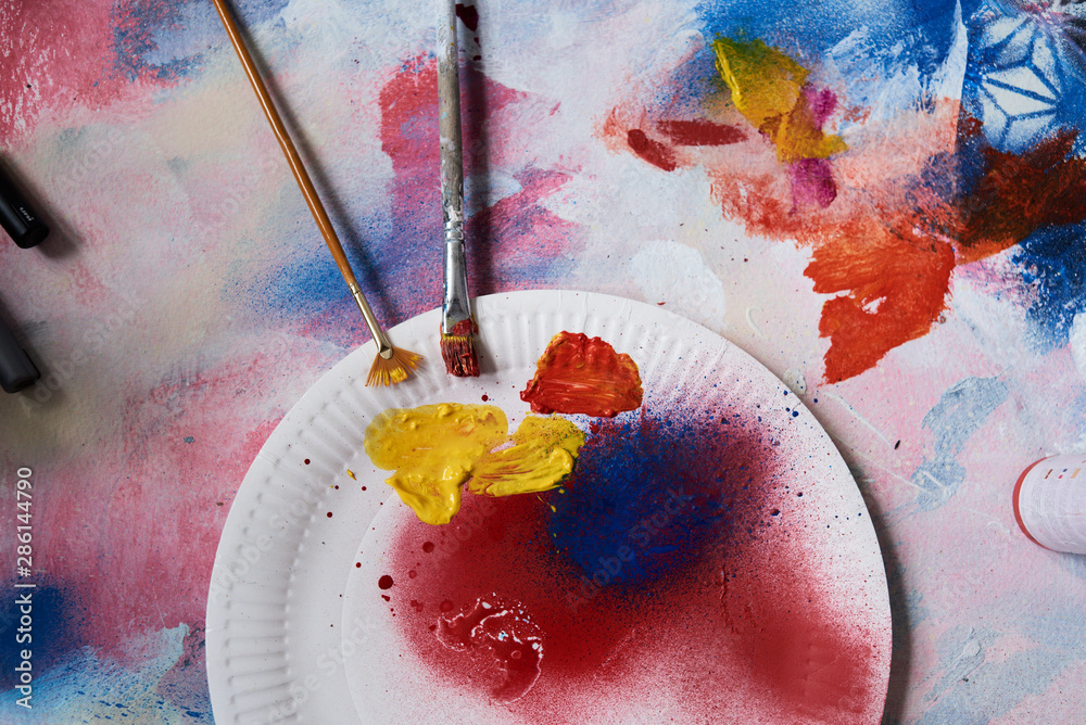 Paper plate with acrylic paints on canvas painting in artist studio ...